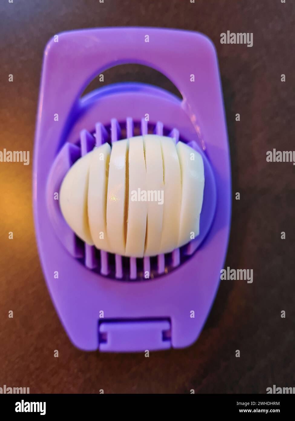 A boiled egg is cut into slices in the egg slicer Stock Photo - Alamy