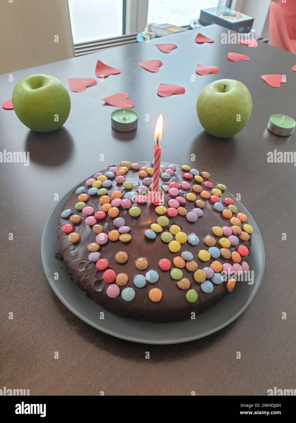 Chocolate cake with Smarties and birthday candle on a birthday plate ...