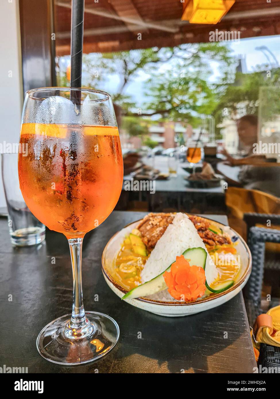An orange-colored summer drink with alcohol in the glass stands next to ...