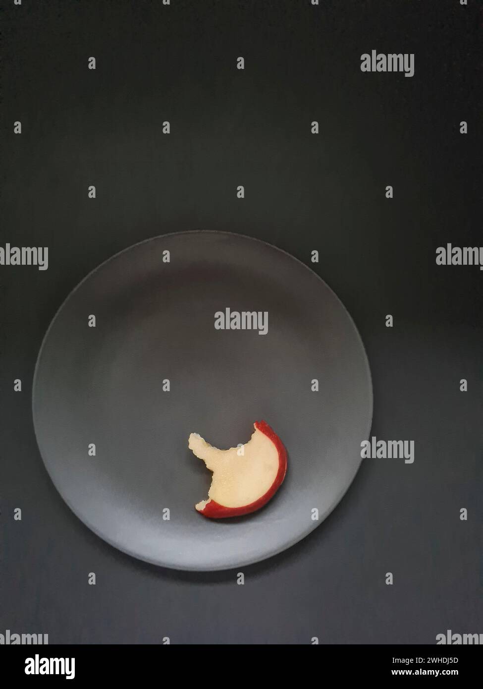 Bitten apple slice on gray plate in front of gray background theme diet ...