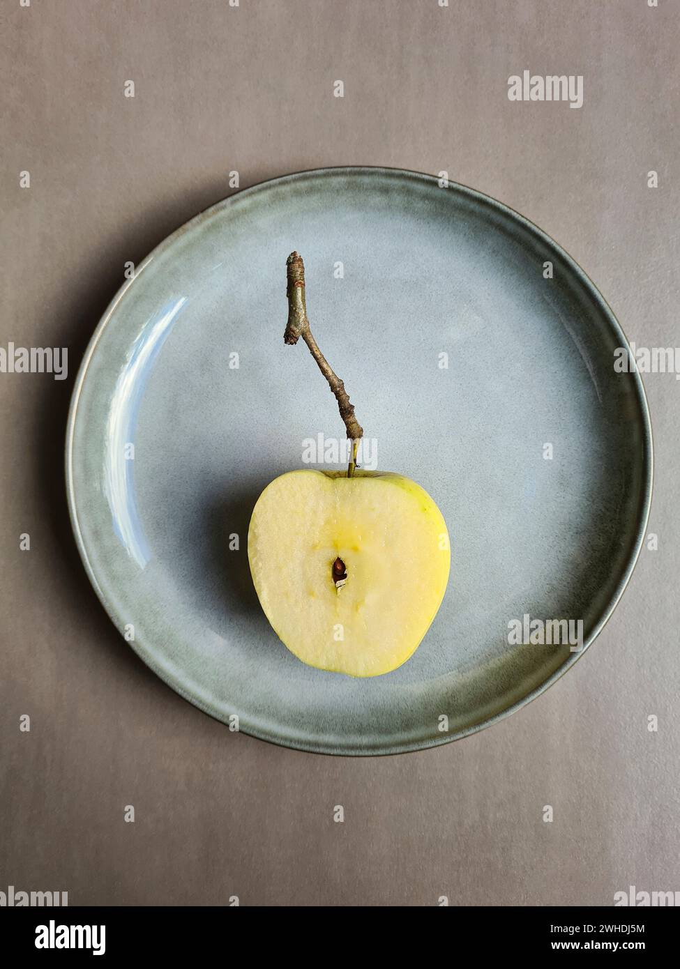 A fresh halved apple with core lies on a pastel-colored plate and light ...