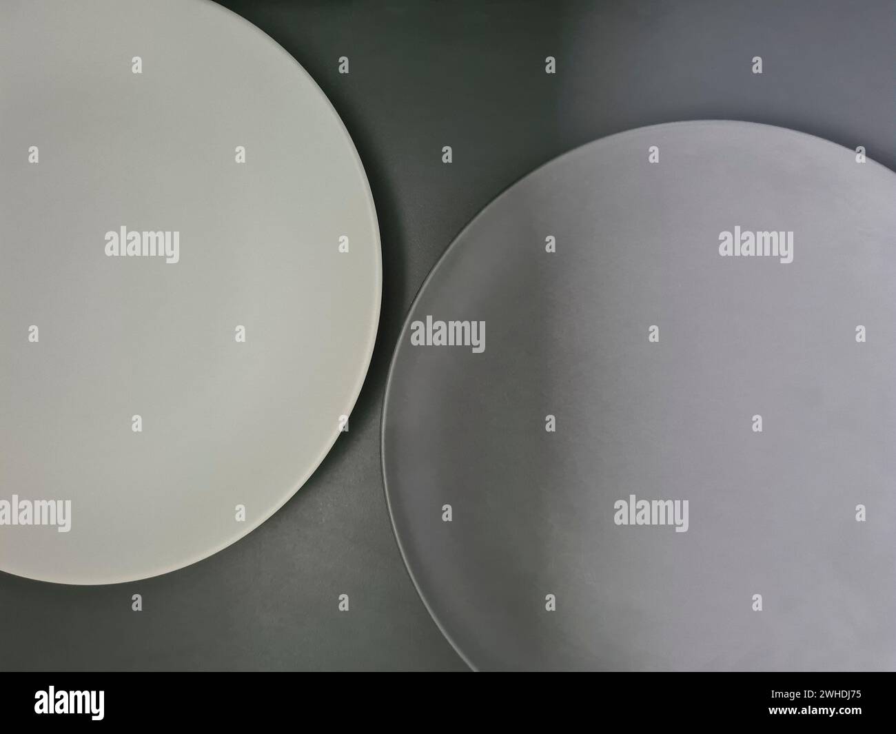 A white and a gray plate on a gray background on the theme of contrasts ...