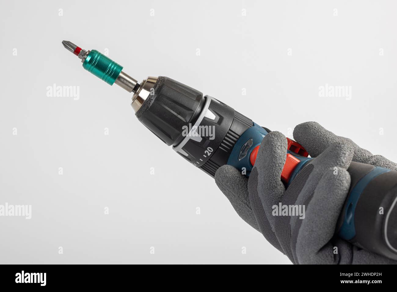 Man's hand with work glove holding cordless drill with bit holder and ...