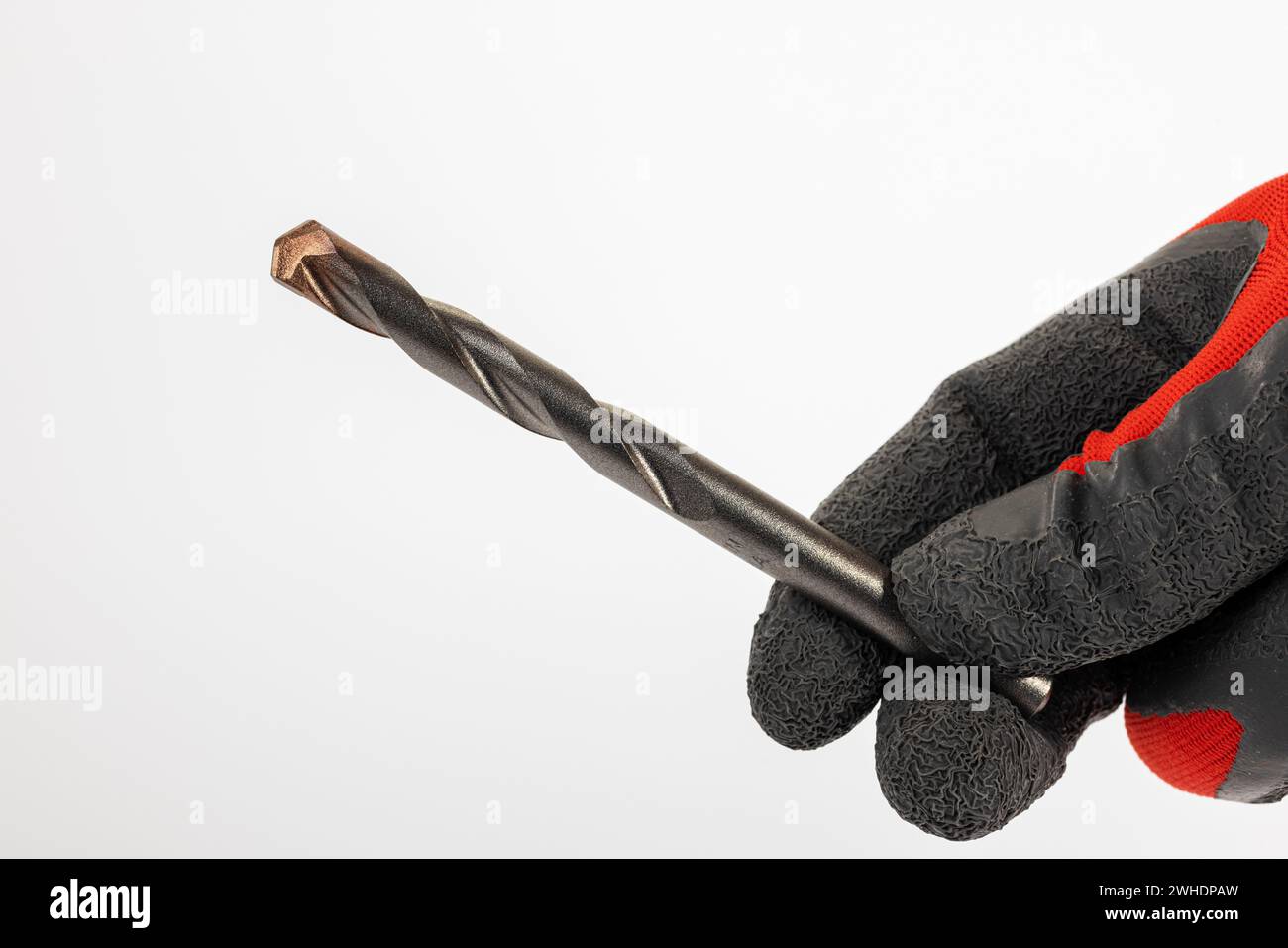 Man's hand with work glove holding 10 mm masonry drill, white ...