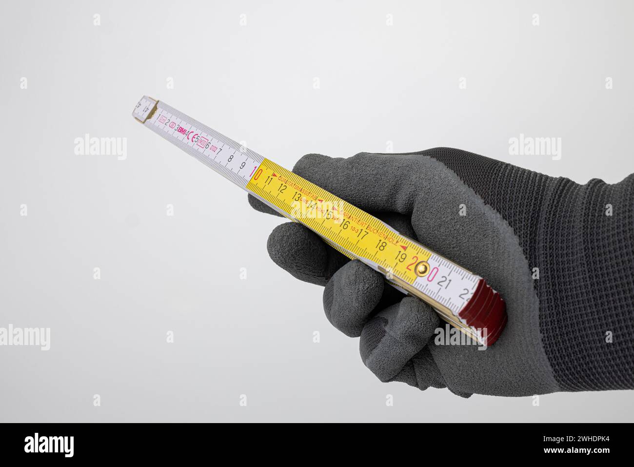 Man's hand with work glove holding folding rule with millimeter and ...