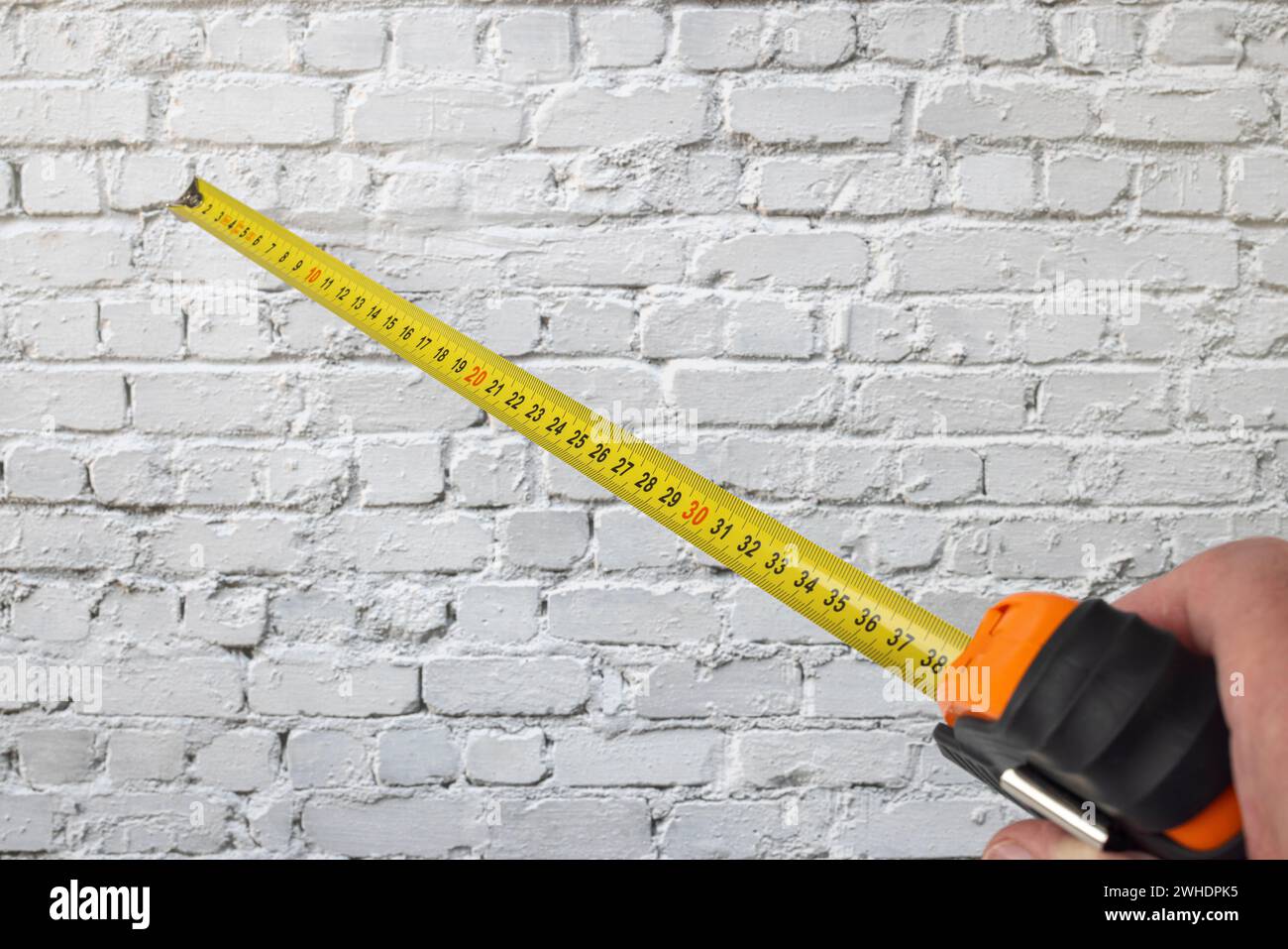 Man's hand holding a yellow measuring tape with millimeter and ...