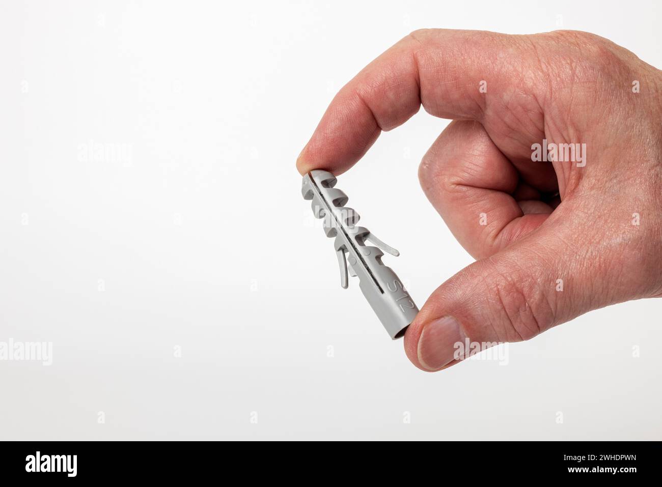Man's hand holding fischer expansion plugs, white background Stock ...