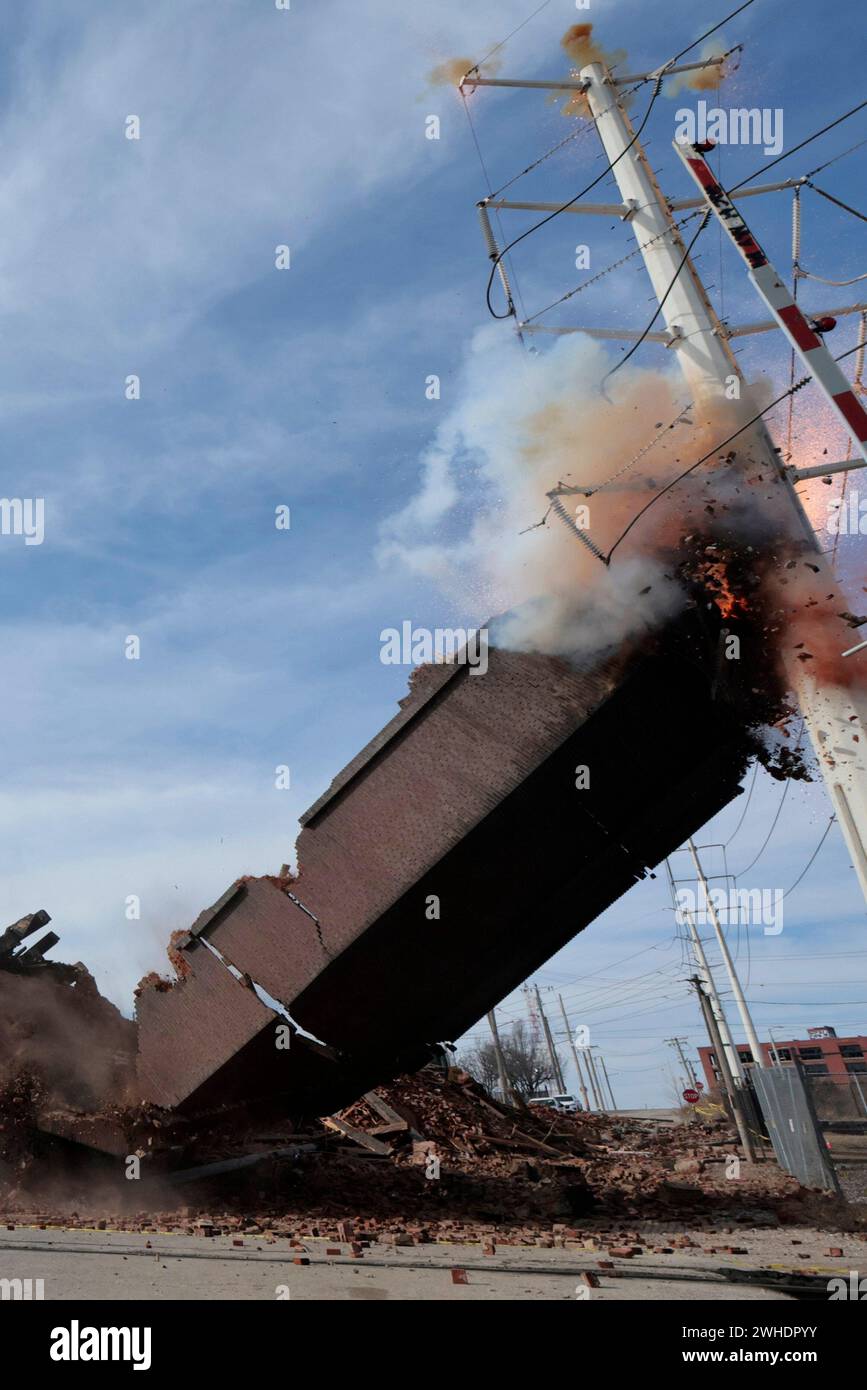 A brief explosion occurs as wrecking crews knock a brick wall into an ...