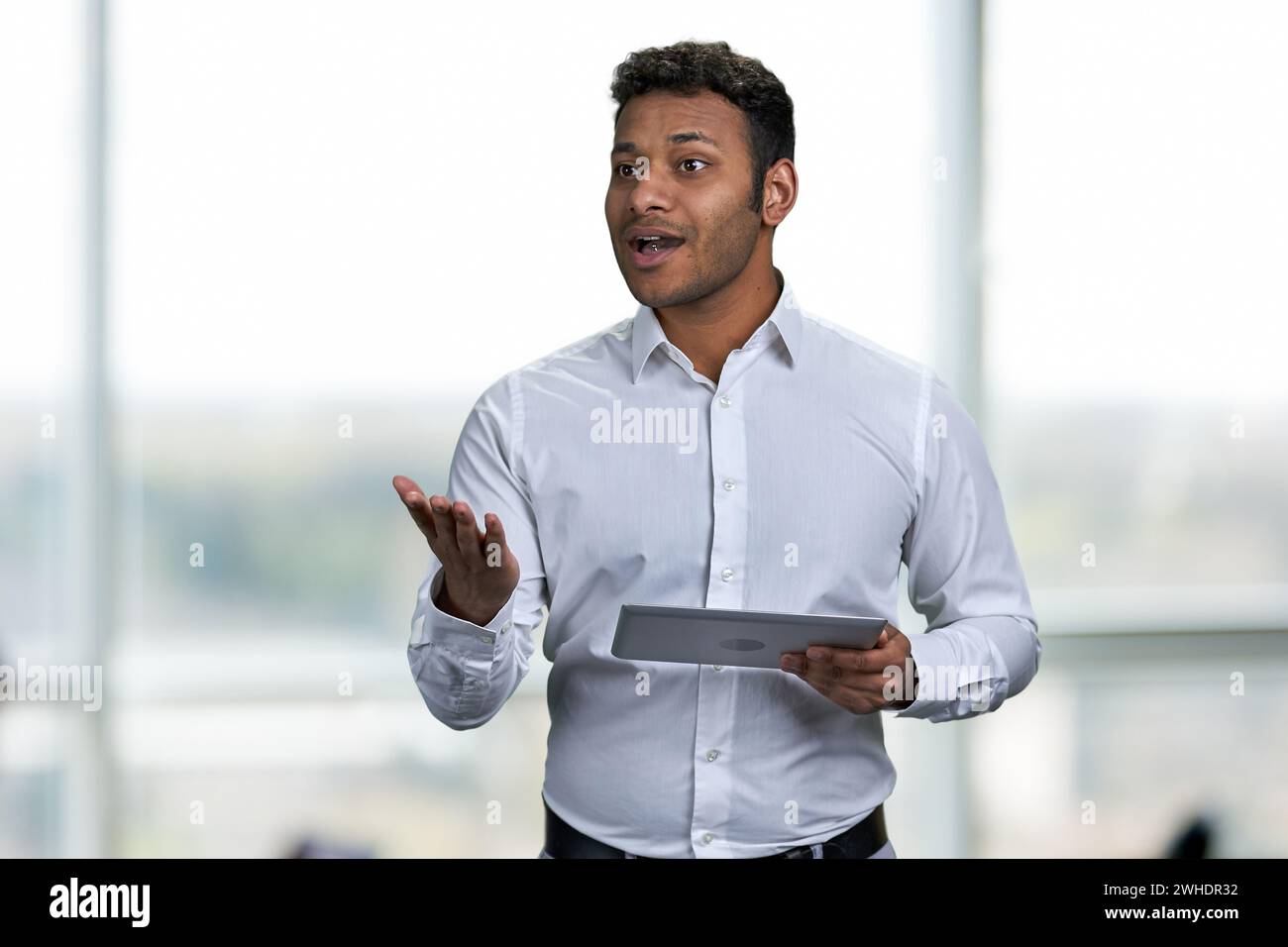 Attractive young businessman giving presentation. Blur interior ...