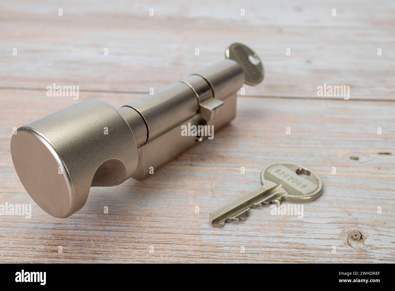 Lock cylinder with rotary knob, key, fixing screw, wooden background ...