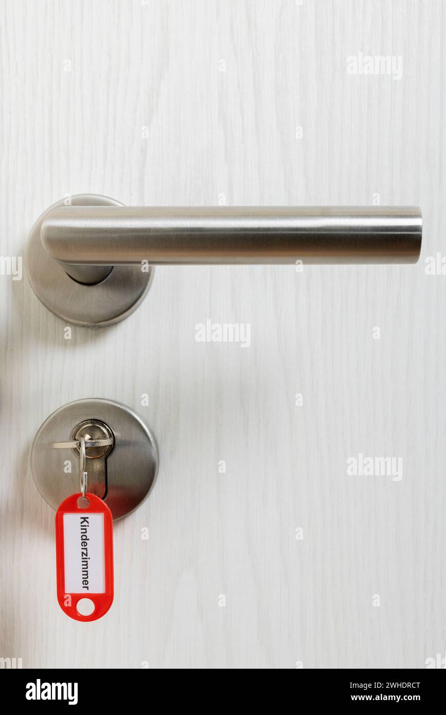 Key with red key ring is inserted in the door lock, labeled ...