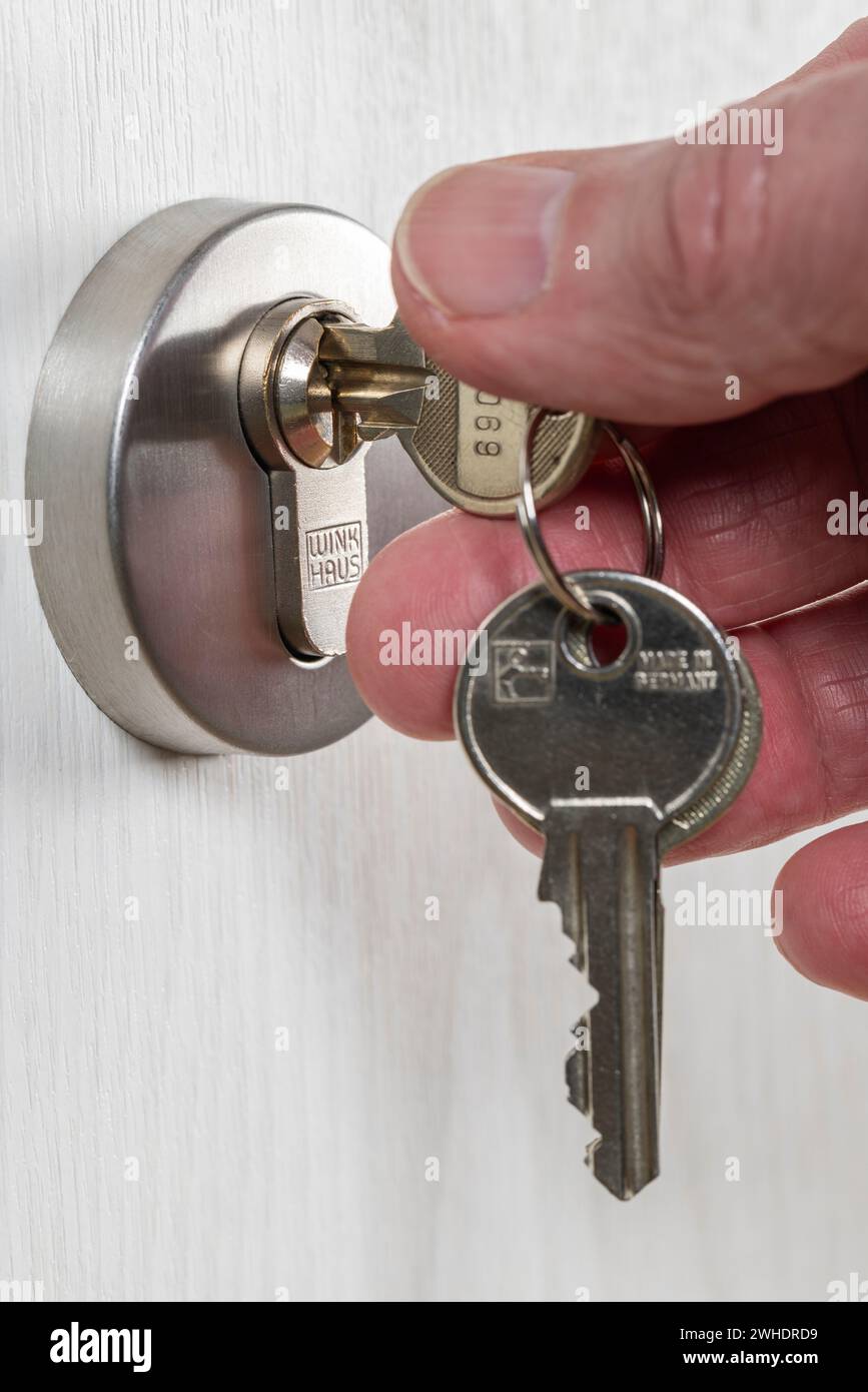 Mans hand with key unlocks door hi-res stock photography and images - Alamy