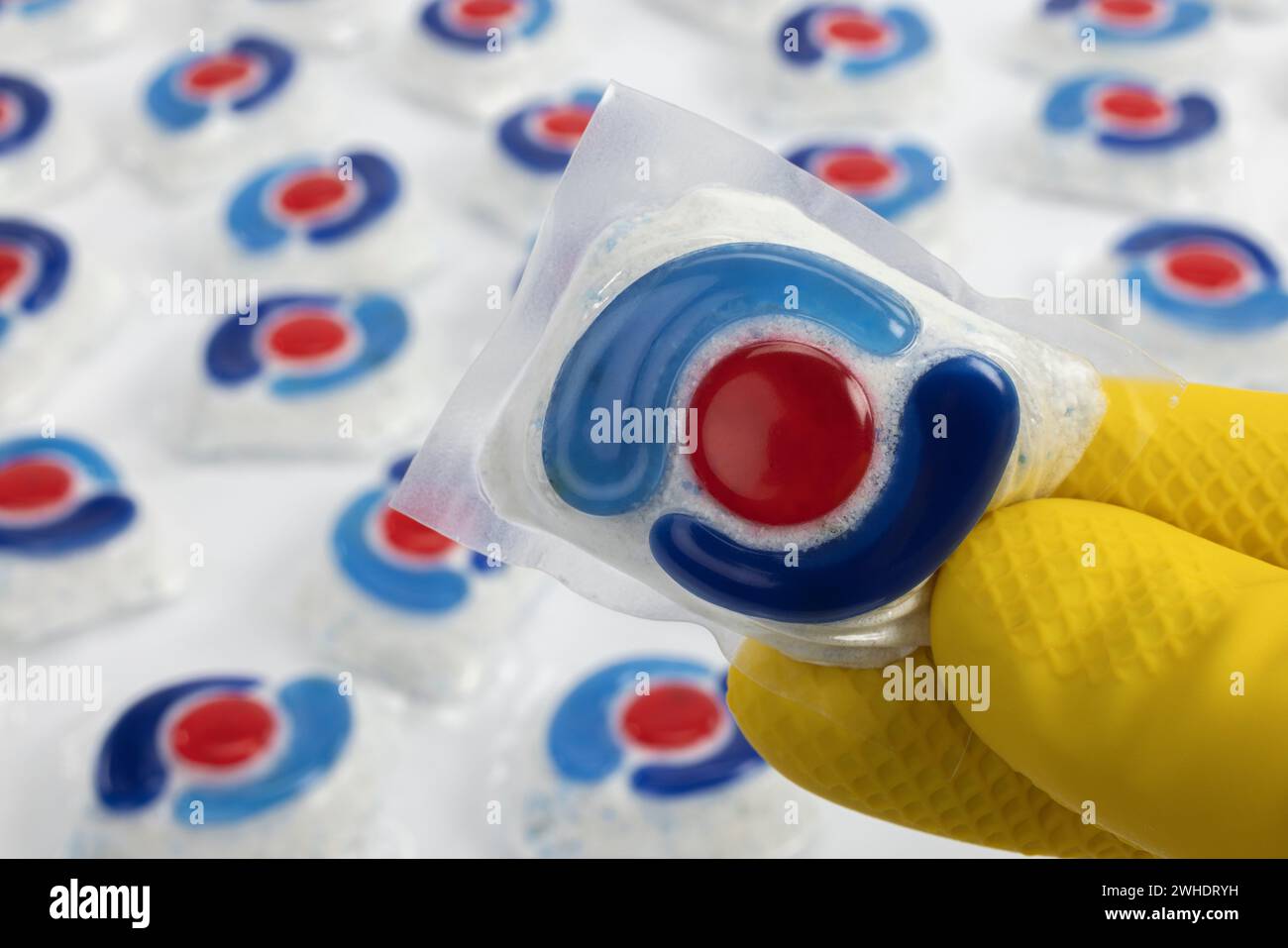 Hand holding dishwasher tab in water-soluble foil, yellow protective ...