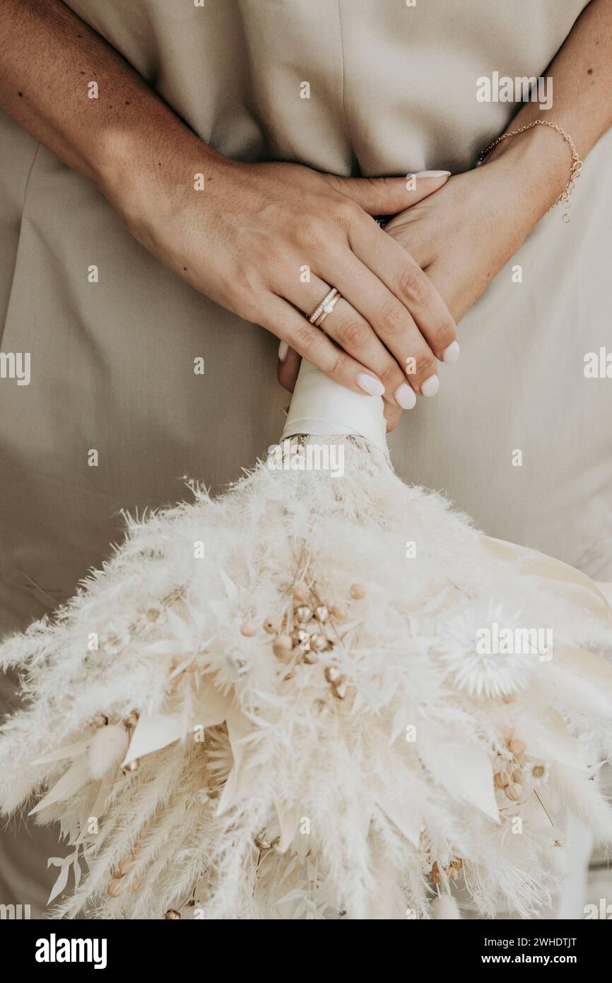 Close-up, bride embraces groom with bouquet of dried flowers, visible ...
