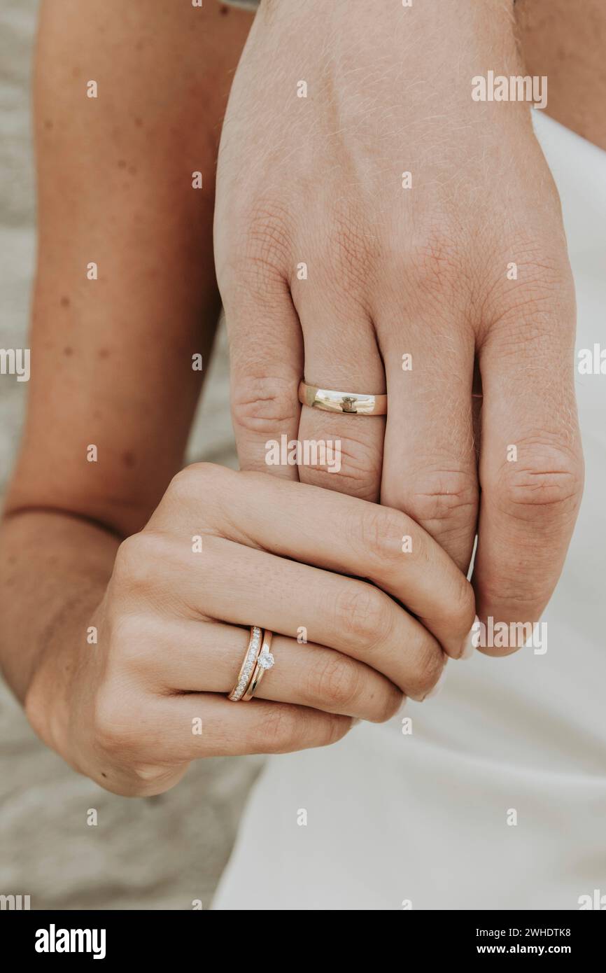 Bride and groom holding hands, wedding rings and engagement ring Stock ...