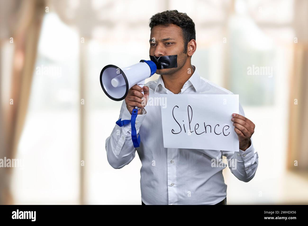Indian man with taped mouth holding poster with inscription Silence ...