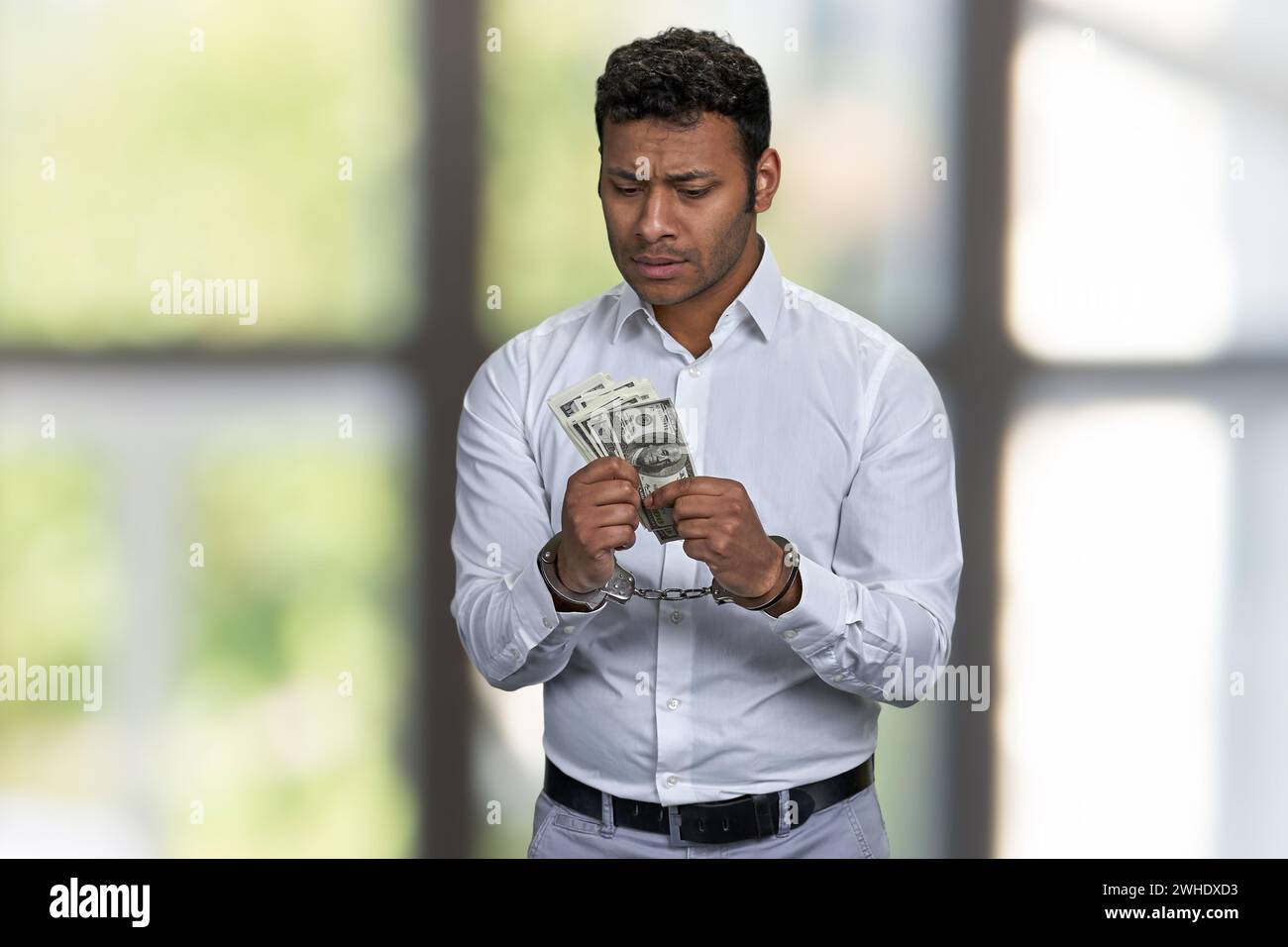 Portrait of handcuffed Indian man holding money. Blur interior ...