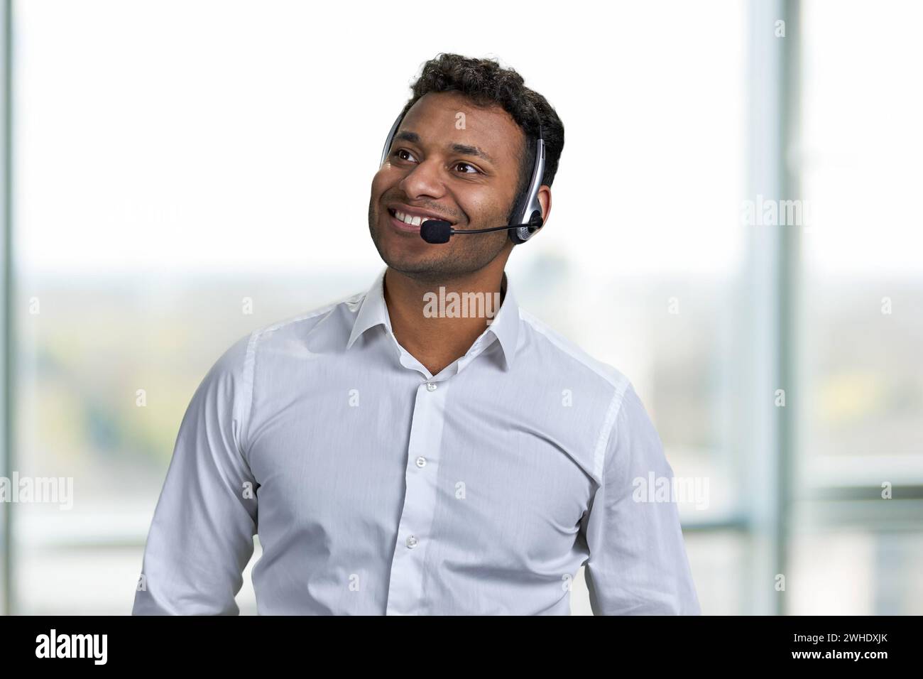 Cheerful male call center operator on blur interior background ...