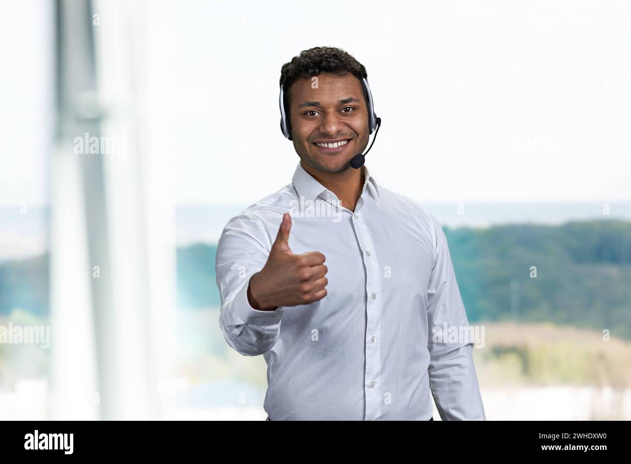 Smiling male call center operator gesturing thumb up. Male call center ...