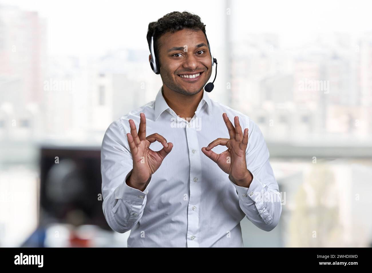 Cheerful male call center operator gesturing okey with both hands. Blur ...