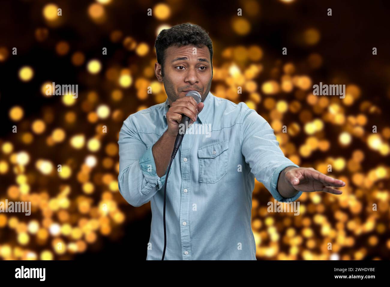 Male performer talking into microphone on festive bokeh background ...