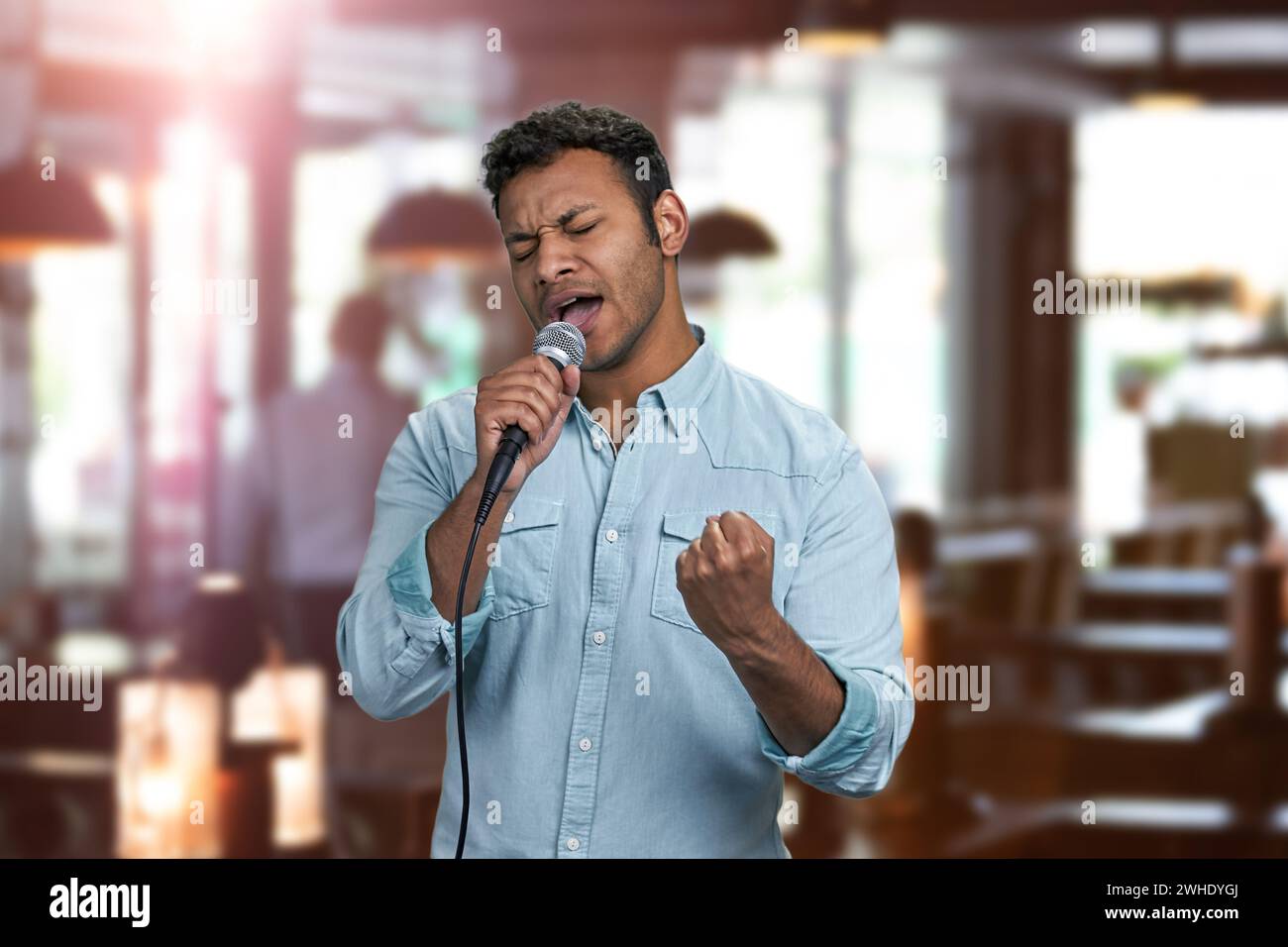 Enthusiastic young indian man performing song with microphone. Interior ...