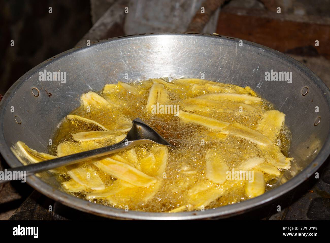 The process of frying banana chips with hot oil, on a large skillet ...