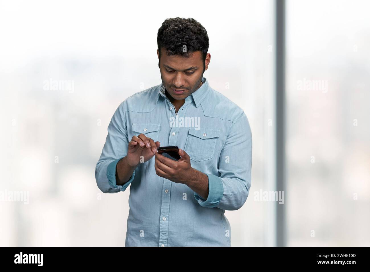 Young Indian man reading message on his mobile phone. Handsome guy ...