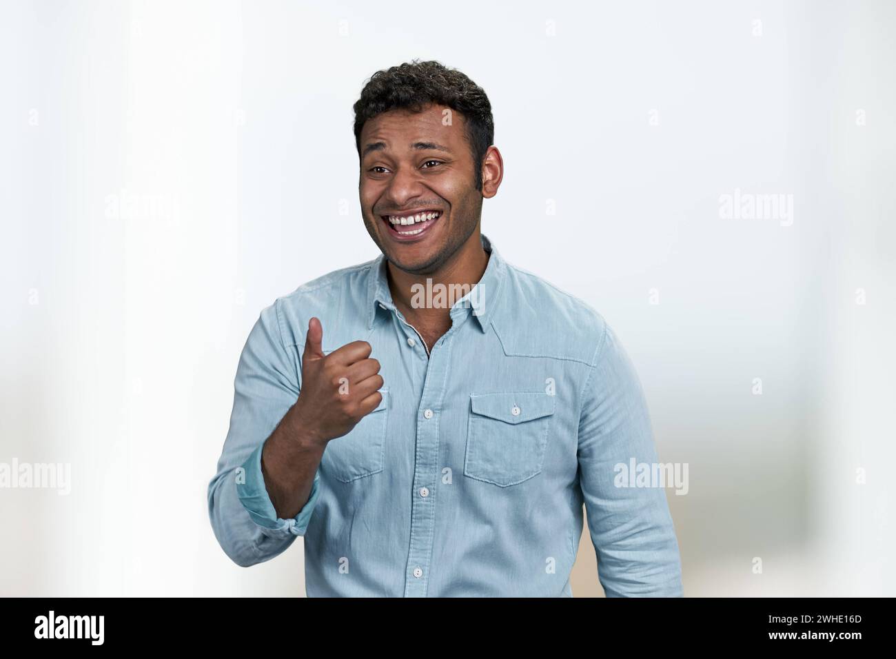 Young laughing man showing thumb up gesture standing on blurred ...