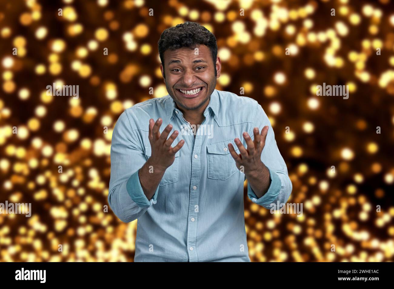Happy cheerful young man expressing happiness on festive bokeh ...
