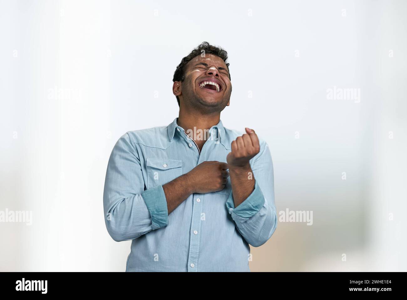 Young indian man is laughing out loud standing on blurred background ...