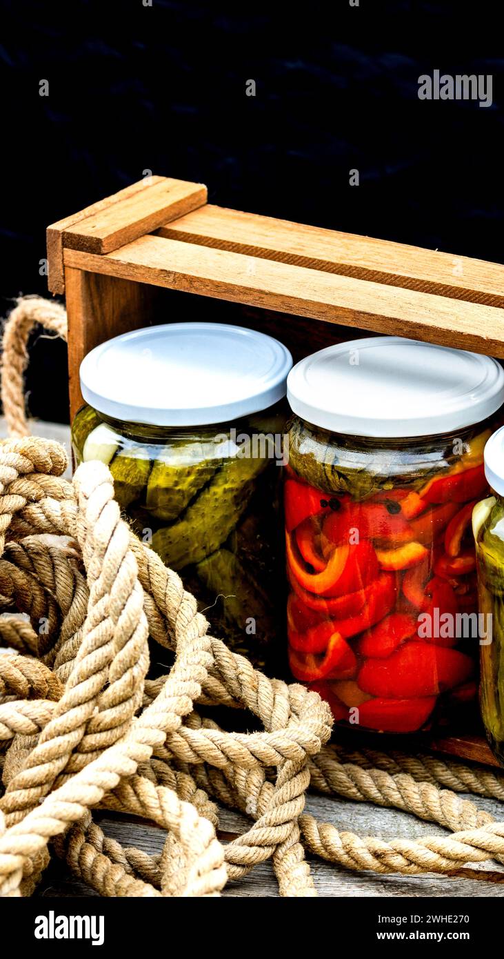 Wooden crate with glass jars with pickled red bell peppers and pickled ...