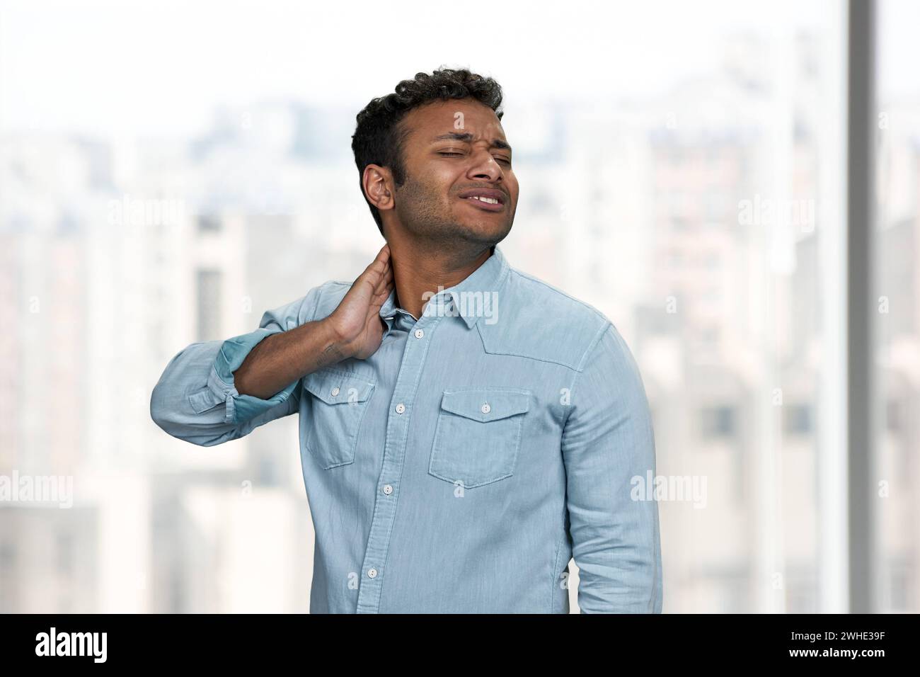 Stressed young man touching his nape. Pain concept. Health problem ...