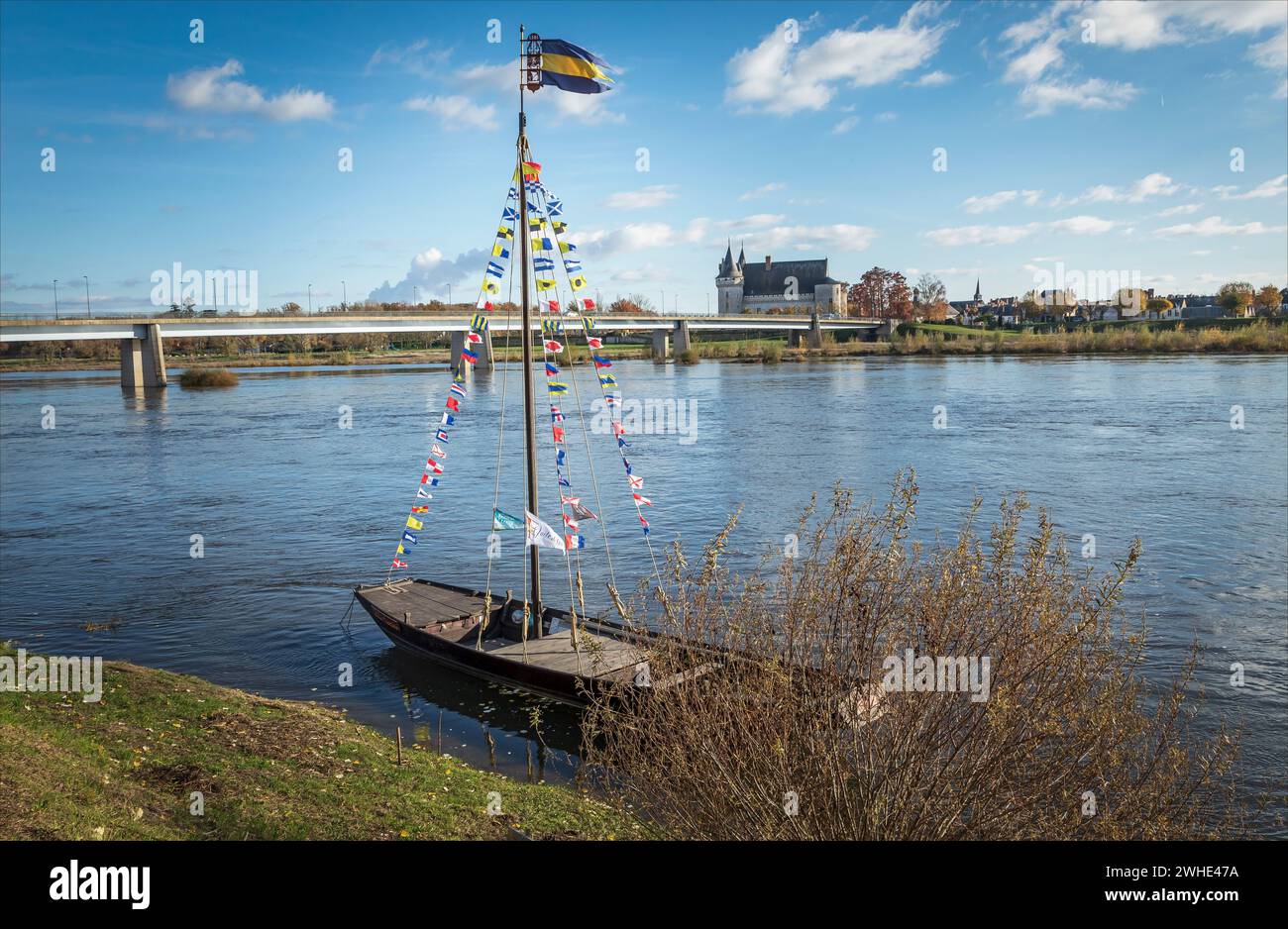 Traditional Loire sailing/fishing boat with flags on the river in front ...
