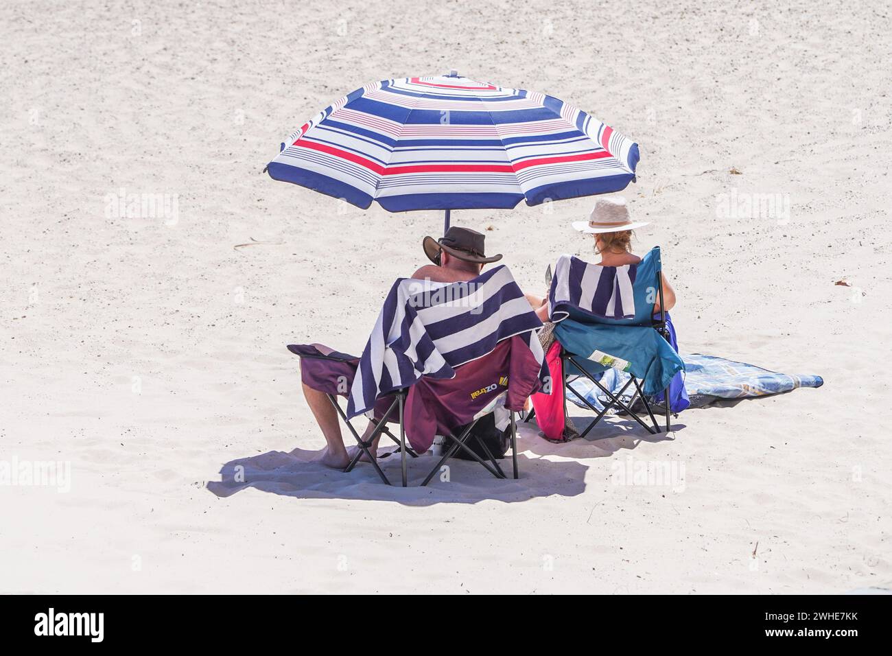 Couple sitting under a beach parasol in Adelaide, Australia Stock Photo ...