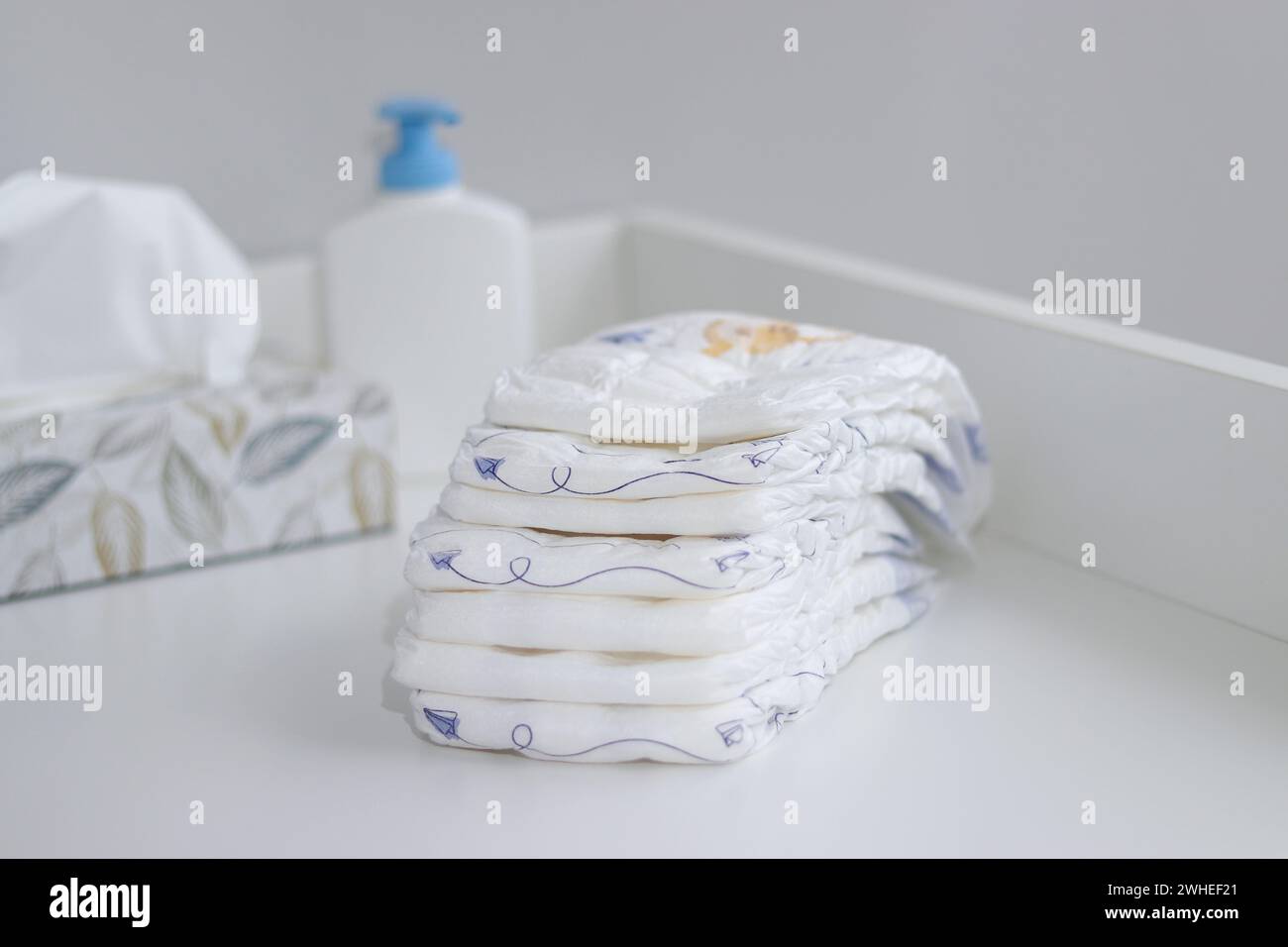 A stack of diapers and baby supplies on white changing table Stock ...
