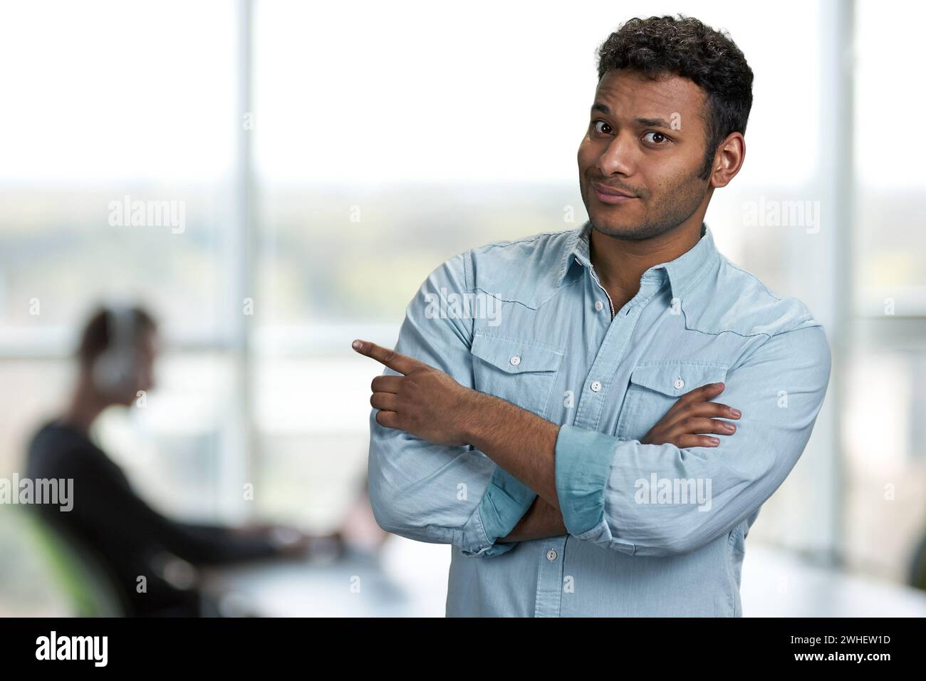 Handsome Indian businessman pointing at copy space. Office interior ...