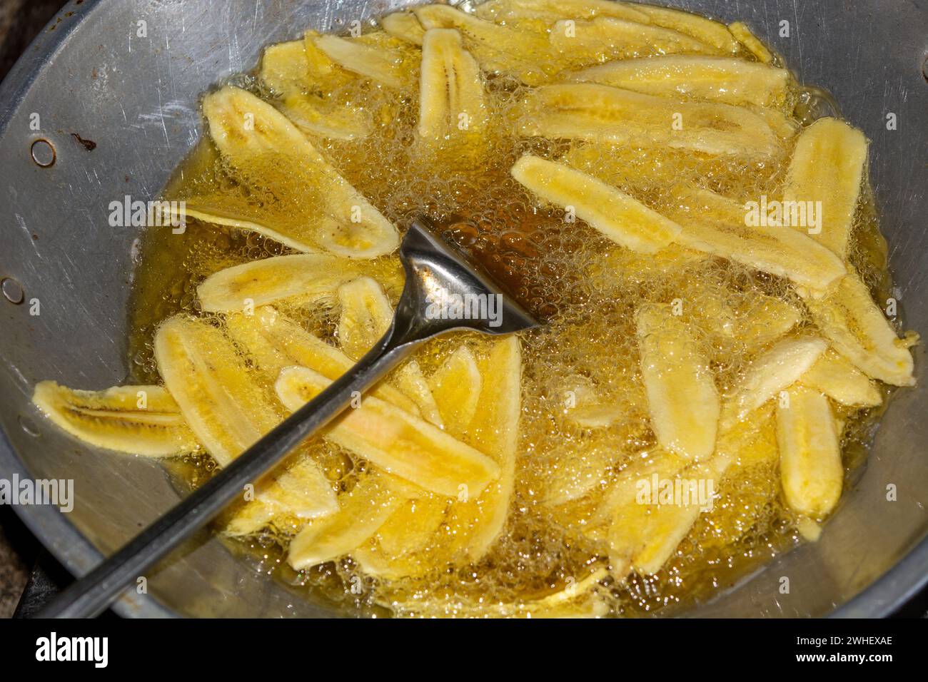 The process of frying banana chips with hot oil, on a large skillet ...
