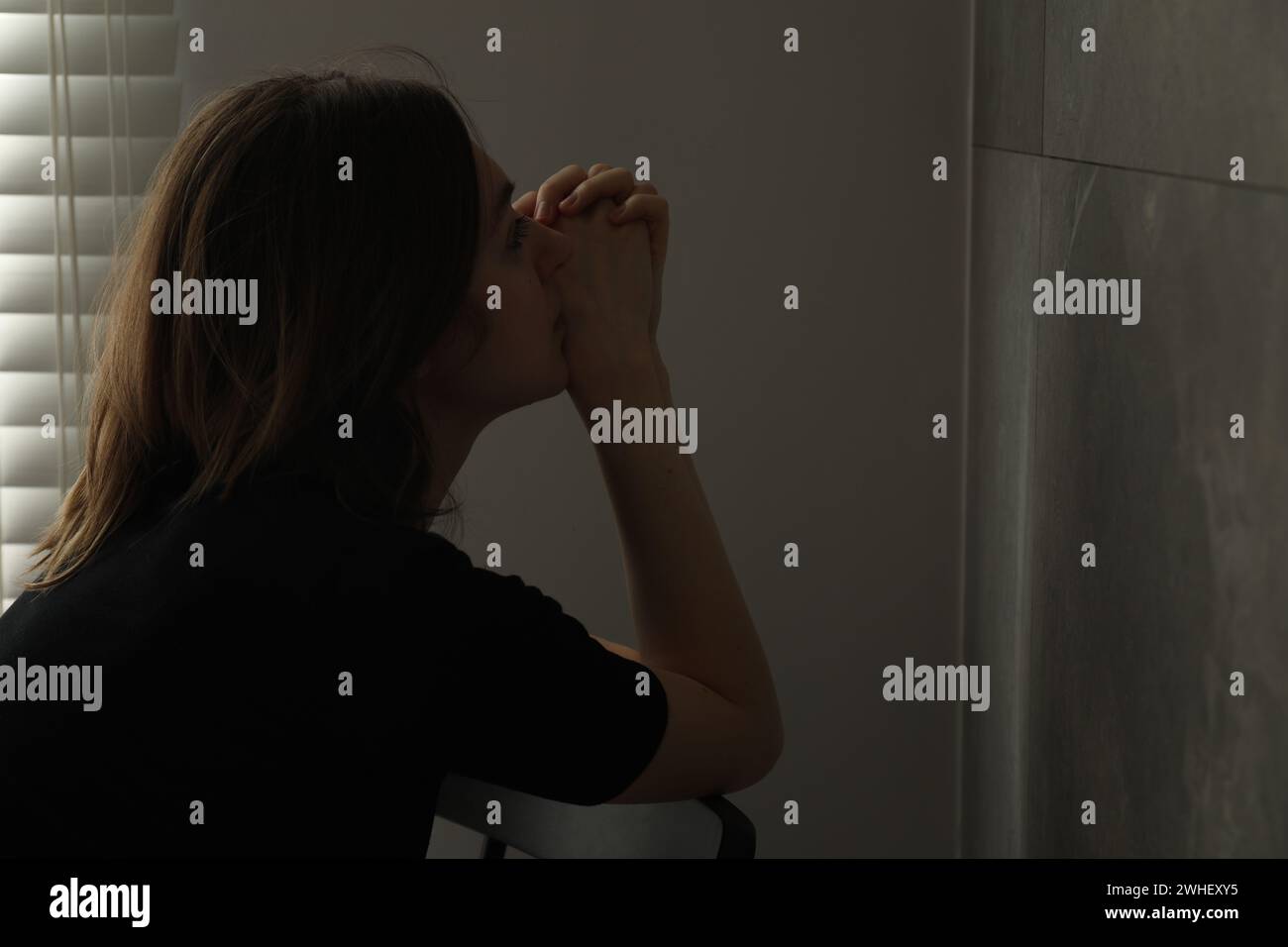 Sad young woman sitting on chair indoors, space for text Stock Photo ...