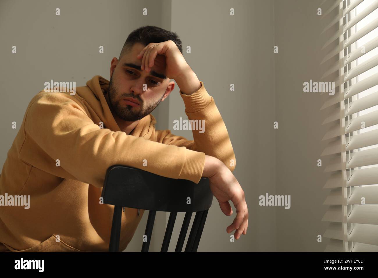 Sad man sitting on chair near window. Space for text Stock Photo - Alamy