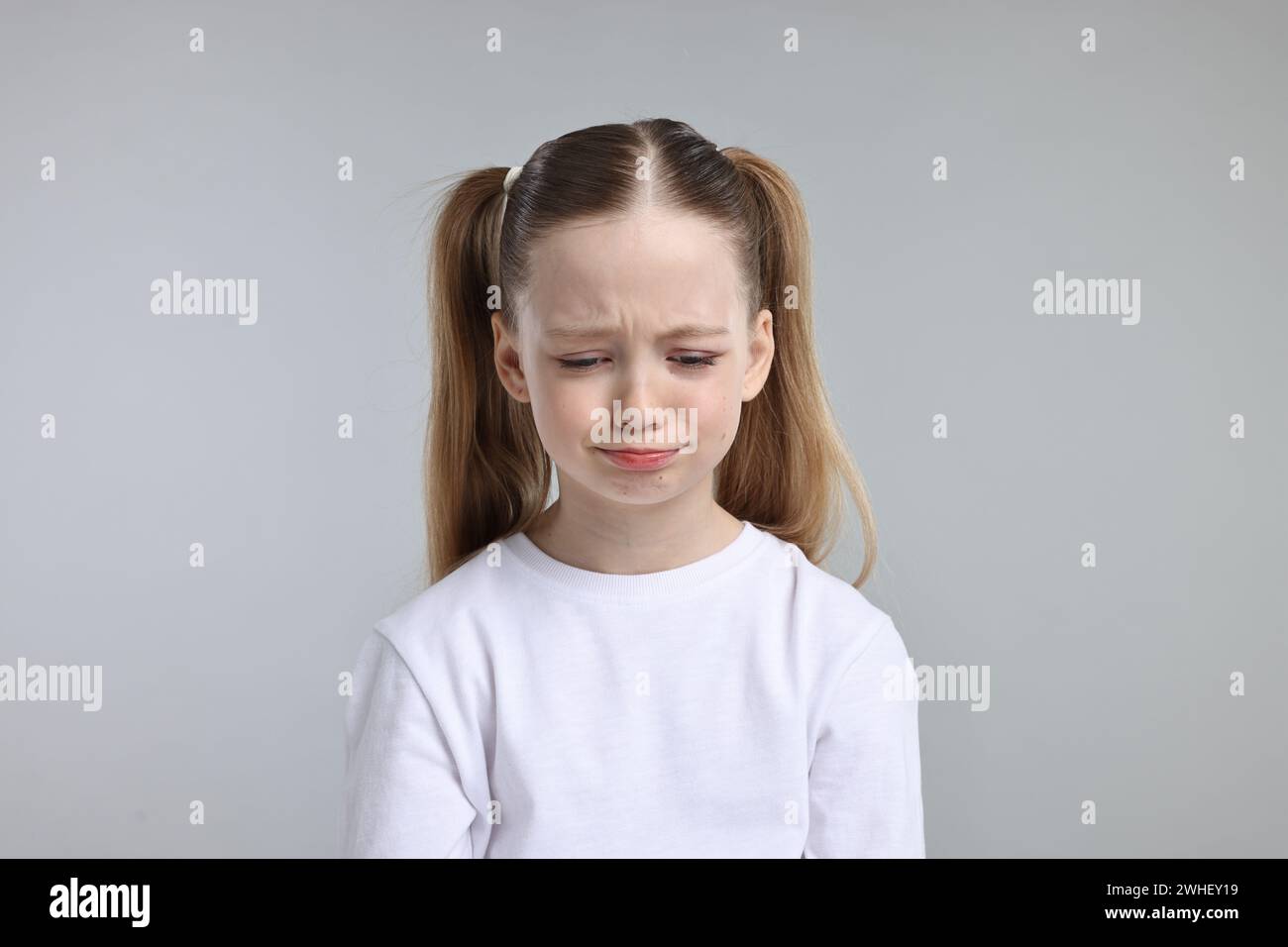 Portrait of sad girl on light grey background Stock Photo - Alamy