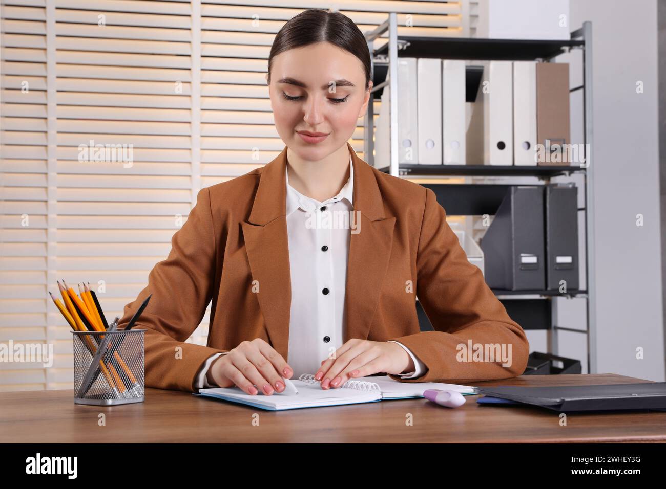 Woman taking notes at wooden table in office Stock Photo - Alamy