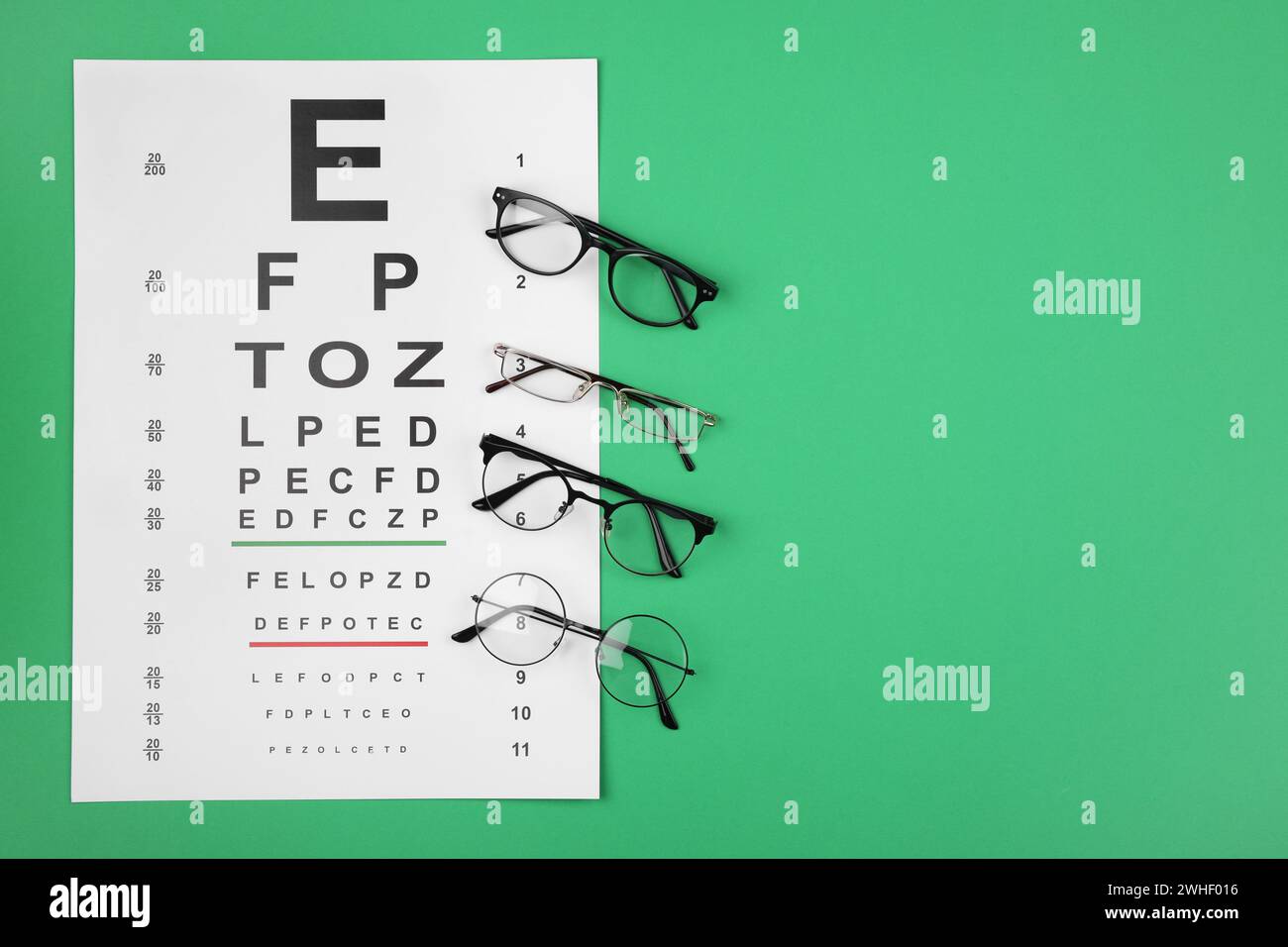 Vision test chart and glasses on green background, flat lay. Space for ...