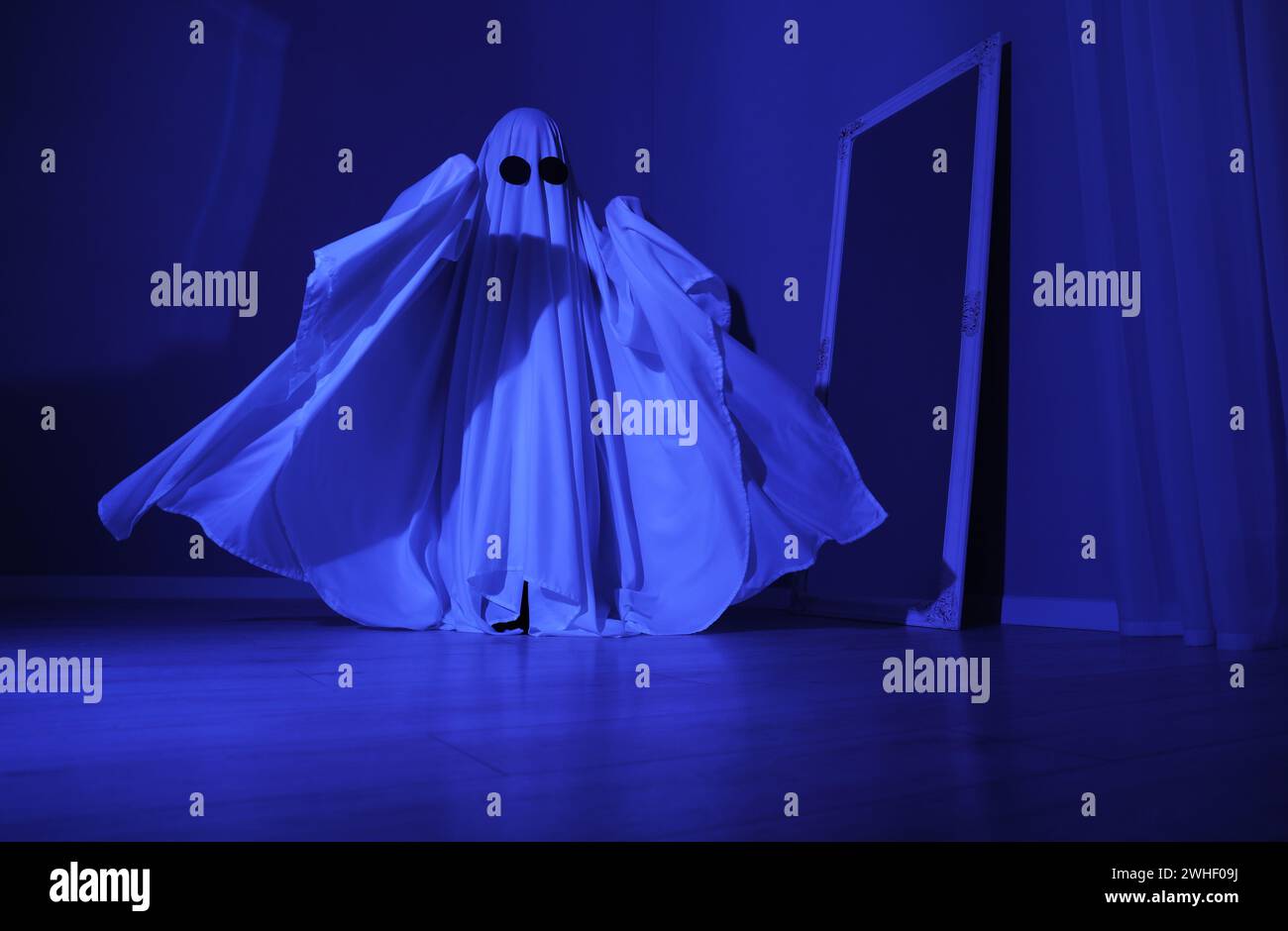 Creepy ghost. Woman covered with sheet in blue light Stock Photo - Alamy