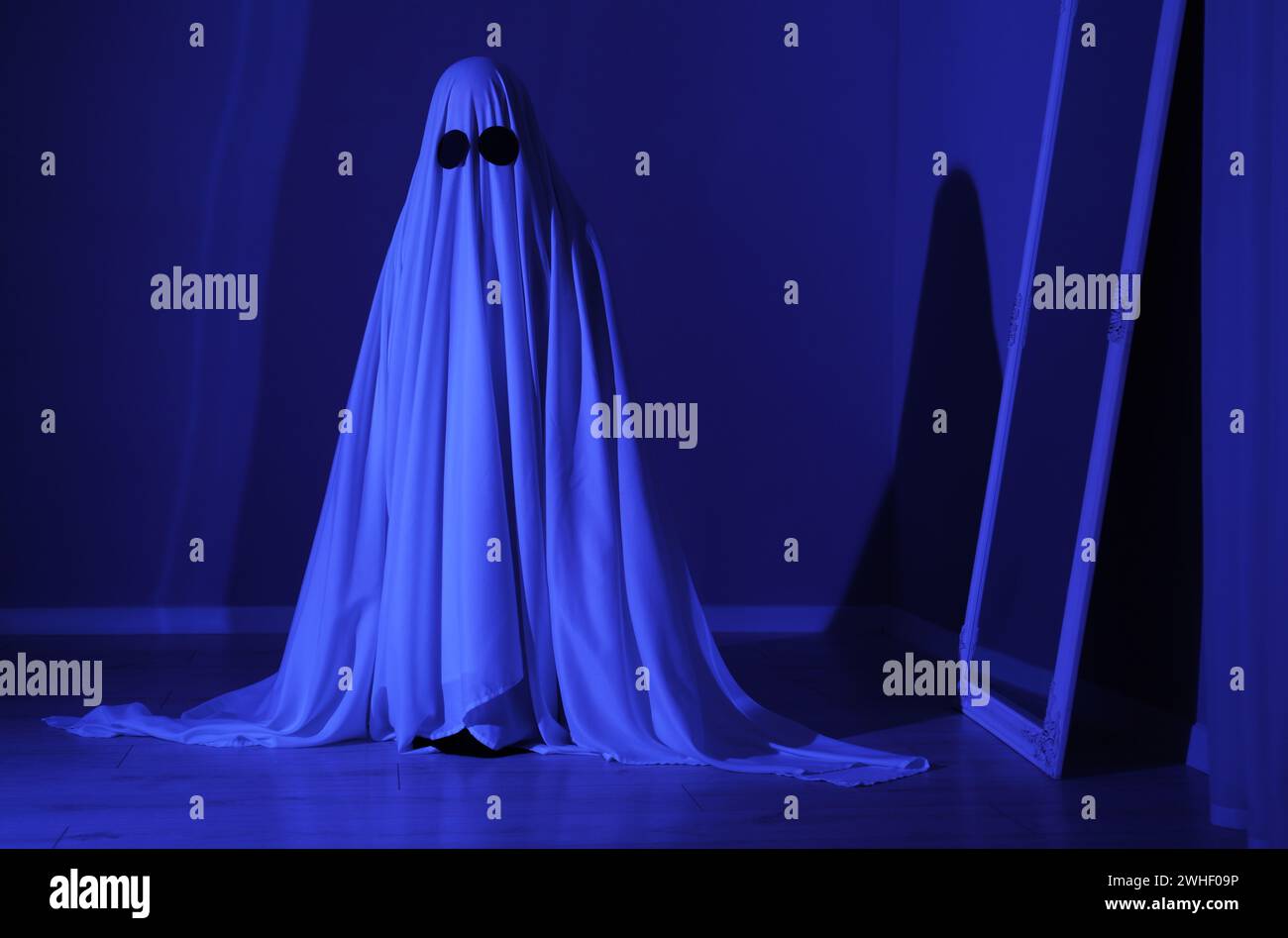 Creepy ghost. Woman covered with sheet in blue light Stock Photo - Alamy