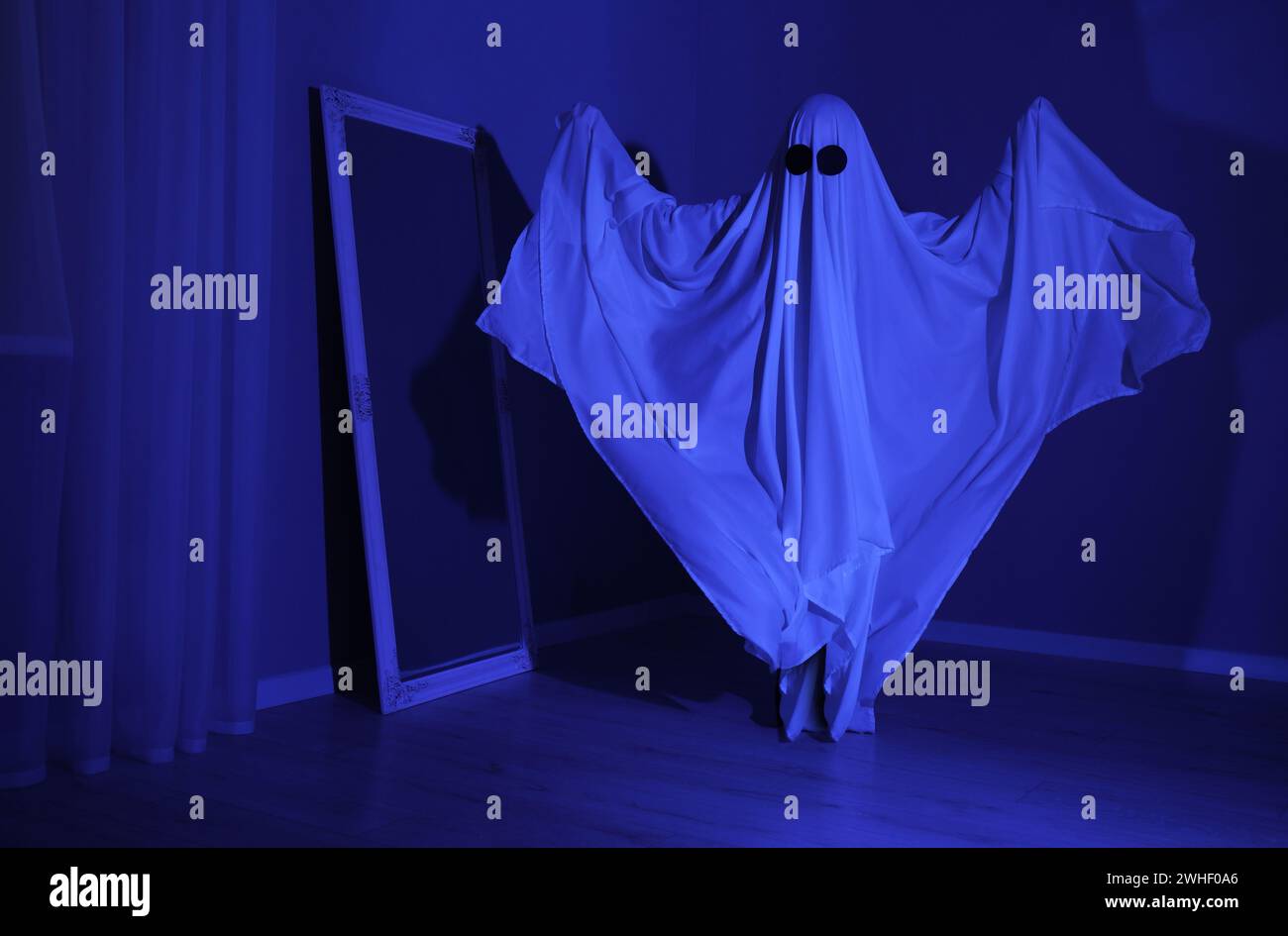 Creepy ghost. Woman covered with sheet in blue light Stock Photo - Alamy