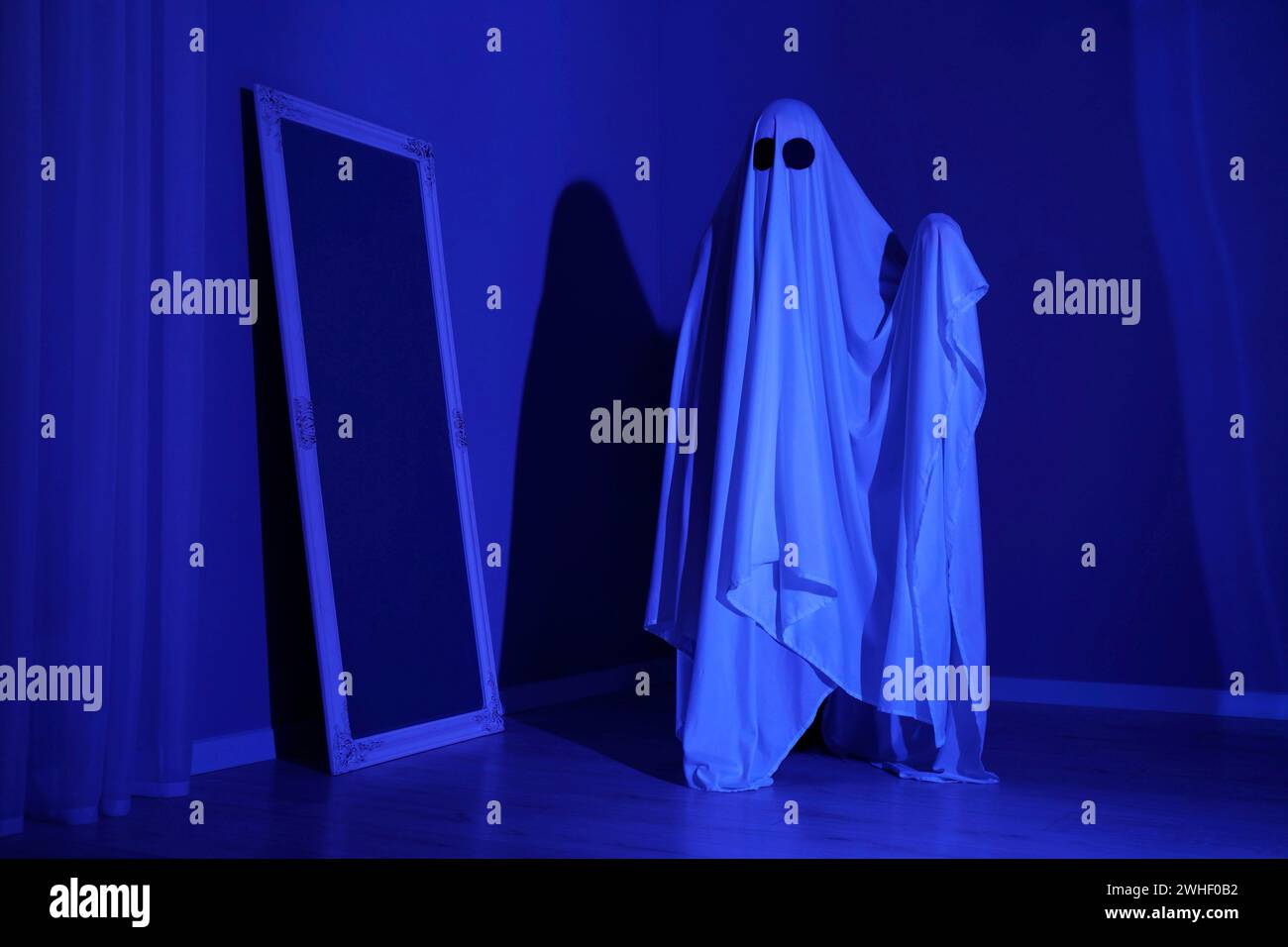Creepy ghost. Woman covered with sheet in blue light Stock Photo - Alamy