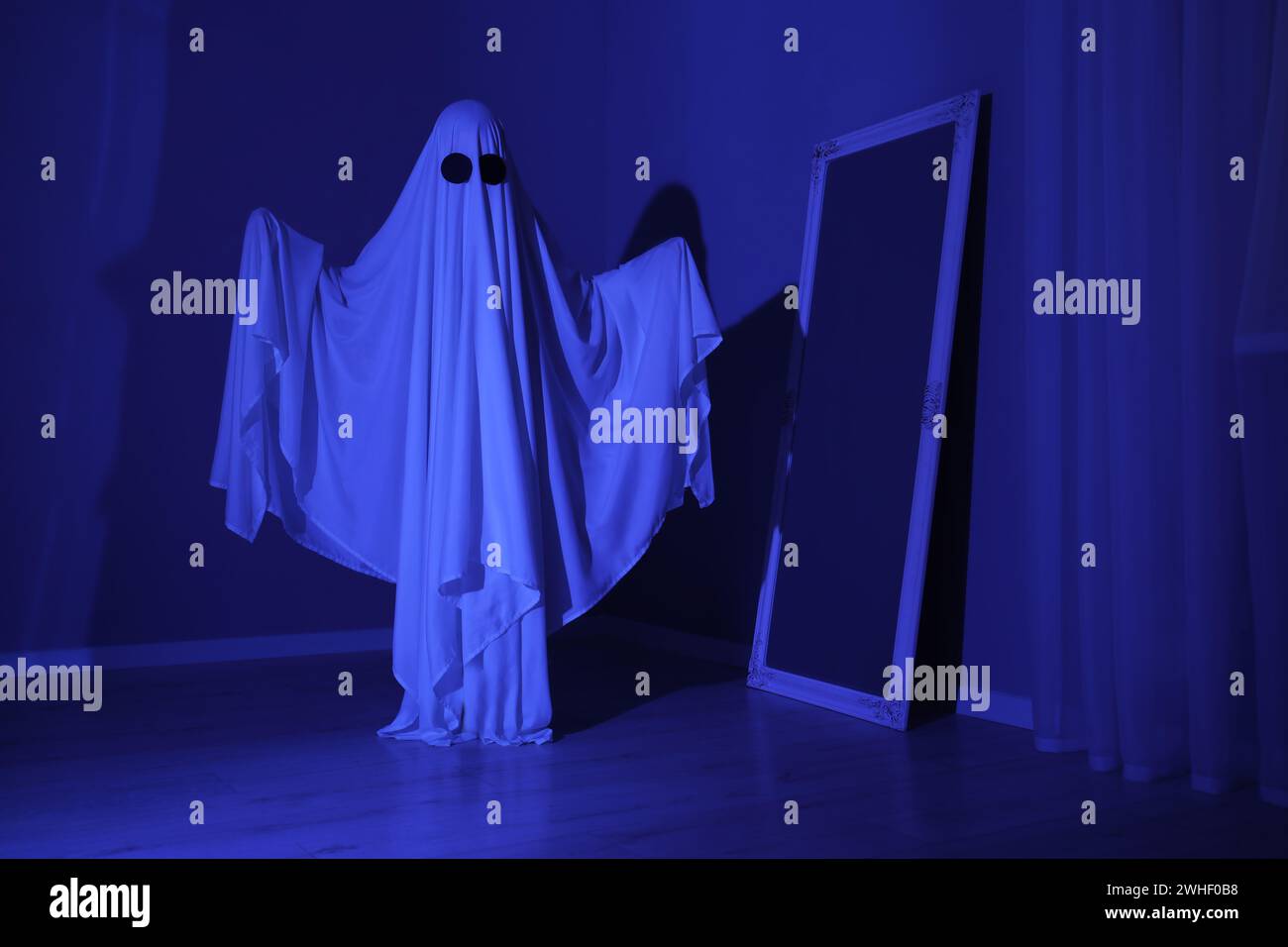 Creepy ghost. Woman covered with sheet in blue light Stock Photo - Alamy