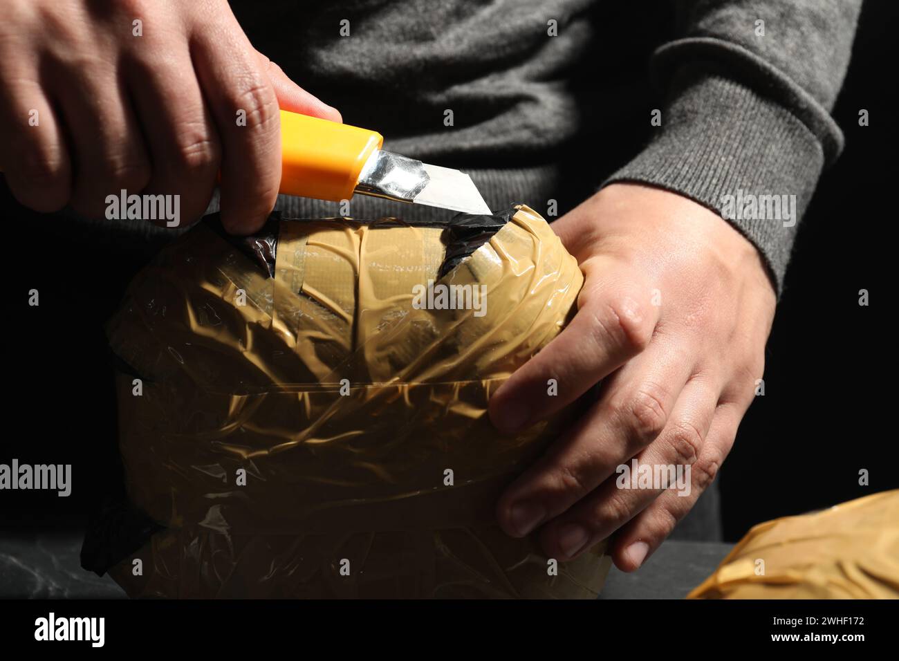 Smuggling and drug trafficking. Man opening package of narcotics with ...