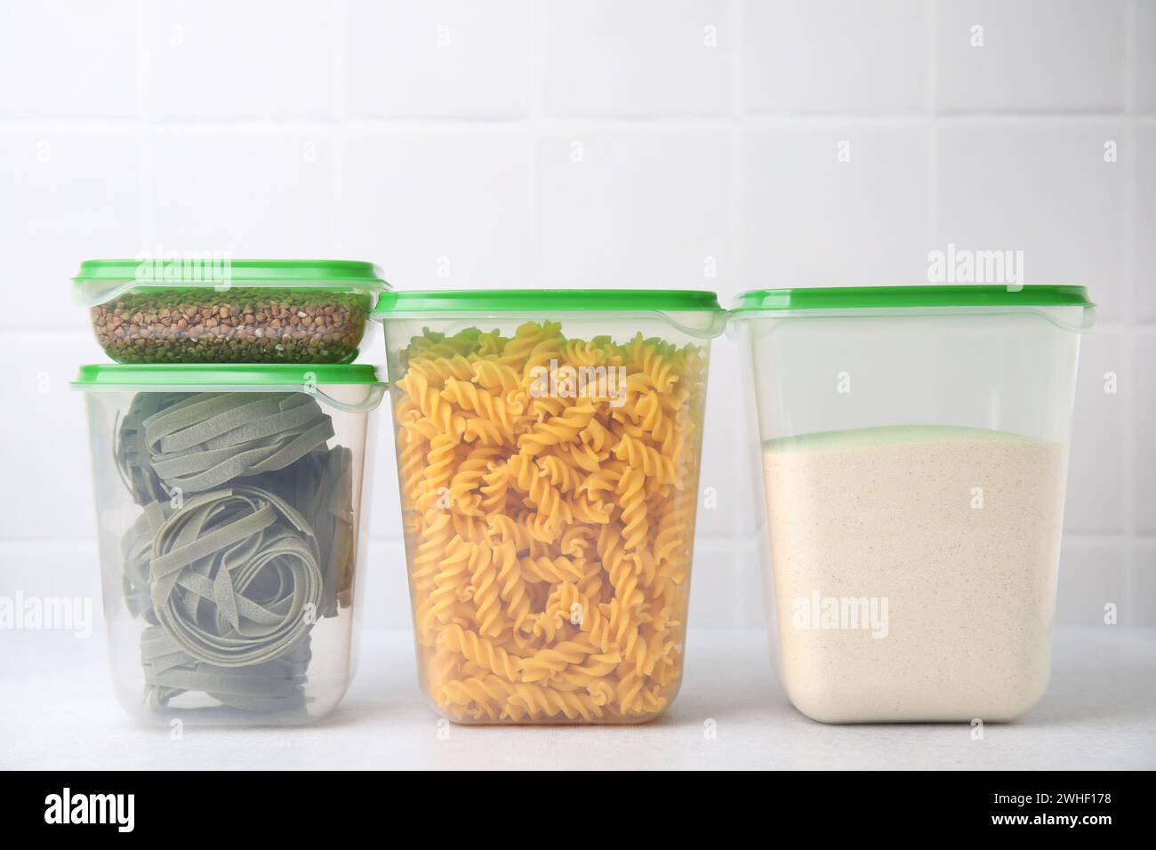 Plastic containers filled with food products on white table near tiled ...